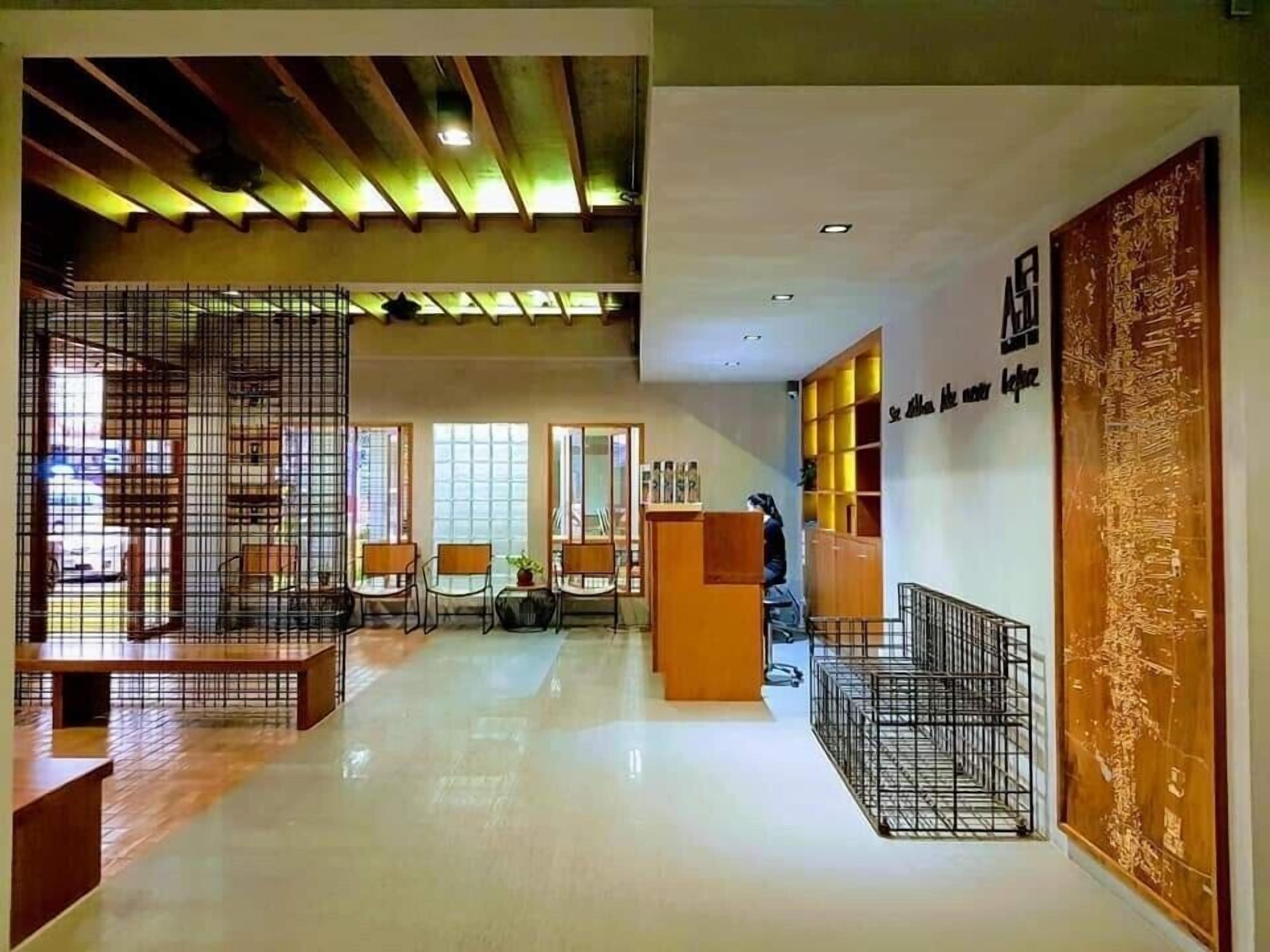 Um hall amplo com teto alto, vigas de madeira e balcão de atendimento.
