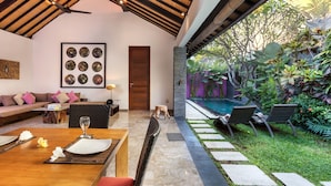 Amplo espaço interno com pé direito alto, piscina e vegetação exuberante no exterior.