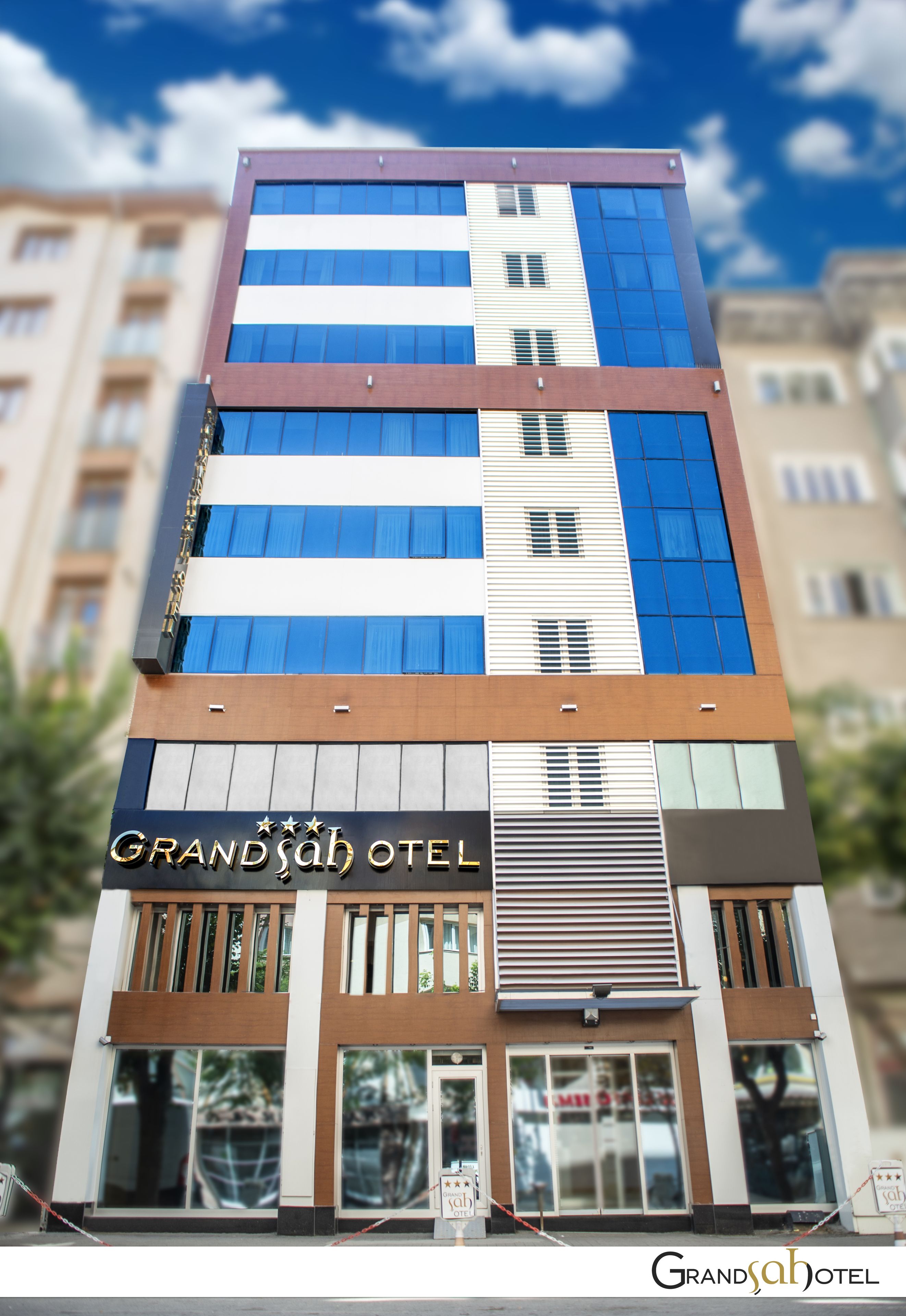 Um hotel com vários andares e uma placa grande com a inscrição 'GrandSah Hotel'.