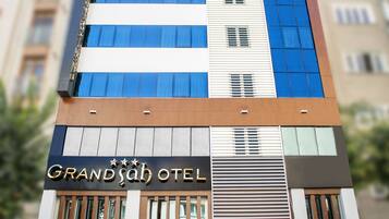 Um hotel com vários andares e uma placa grande com a inscrição 'GrandSah Hotel'.