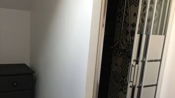 Casa de banho moderna com cabine de duche em vidro, cómoda de madeira escura e azulejos estampados.