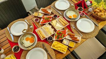 Mesa posta com diversos itens de café da manhã, incluindo ovos, queijo e pão.