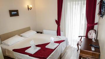 Quarto de hotel com duas camas, uma mesa de cabeceira de madeira, uma cadeira e uma escrivaninha com televisão e controles remotos.