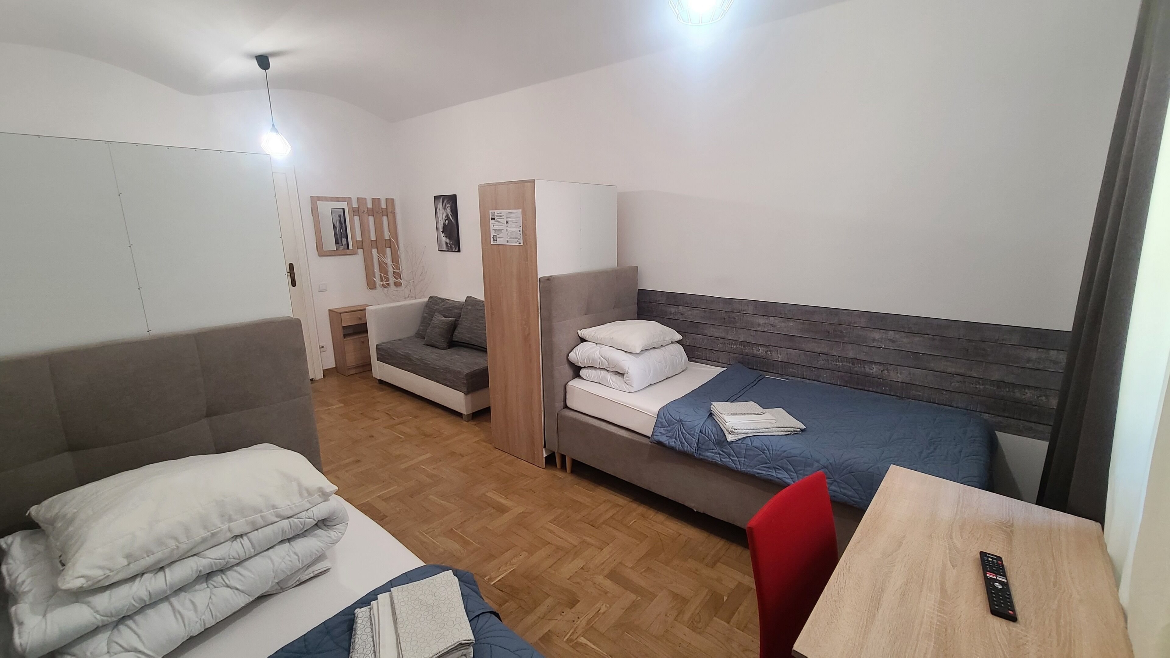 Quarto de hotel pequeno com uma cama, um sofá, uma mesinha e uma escrivaninha.