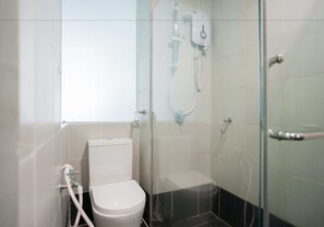 Uma casa de banho moderna com sanita, cabine de duche em vidro e porta em vidro.