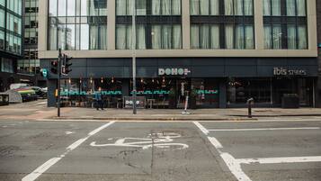 Um edifício moderno com um café chamado 'DOHO' e uma loja chamada 'ibis styles'.