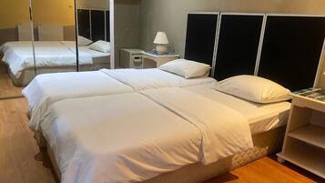 Quarto de hotel com duas camas, uma mesa de cabeceira com luminária e um espelho.