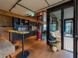 Uma área de bar moderna, com balcão, banquetes e um espaço de estar com vista.