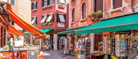 Uma rua estreita com edifícios coloridos, mesas ao ar livre e diversas lojas.