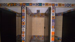Casa de banho com padrões de azulejos coloridos, zona de duche e uma porta.