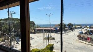 Vista da janela sobre uma área costeira, com céu claro, estrada e alguns edifícios.