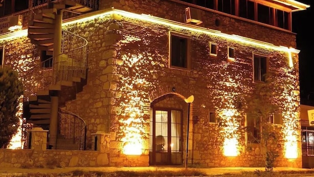 Um edifício de pedra com varanda e escadaria, iluminado à noite.