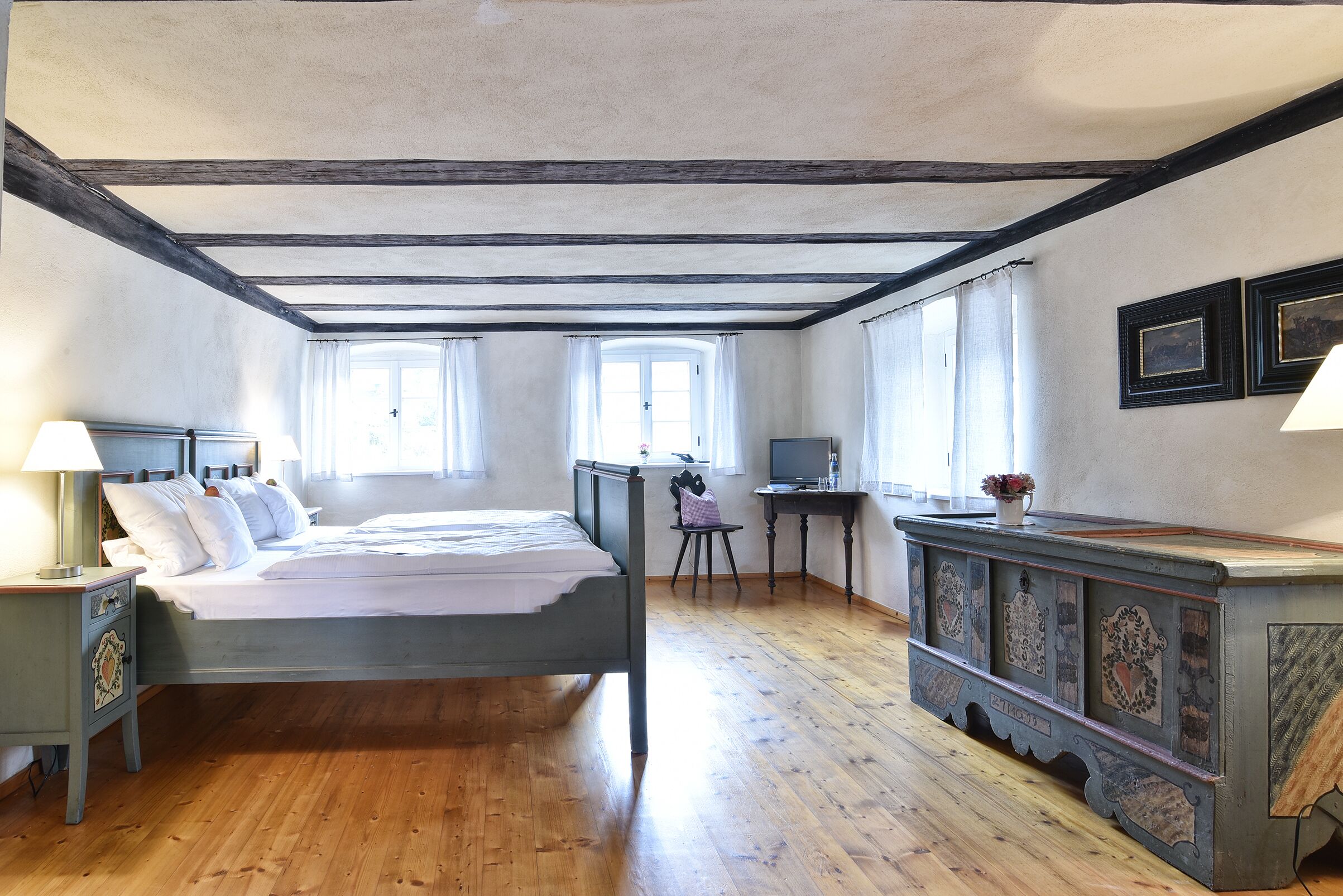 Quarto com cama, escrivaninha, cadeira e cómoda.