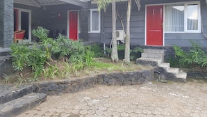 Uma casa com telhado de telhas, parede de pedra e porta vermelha.