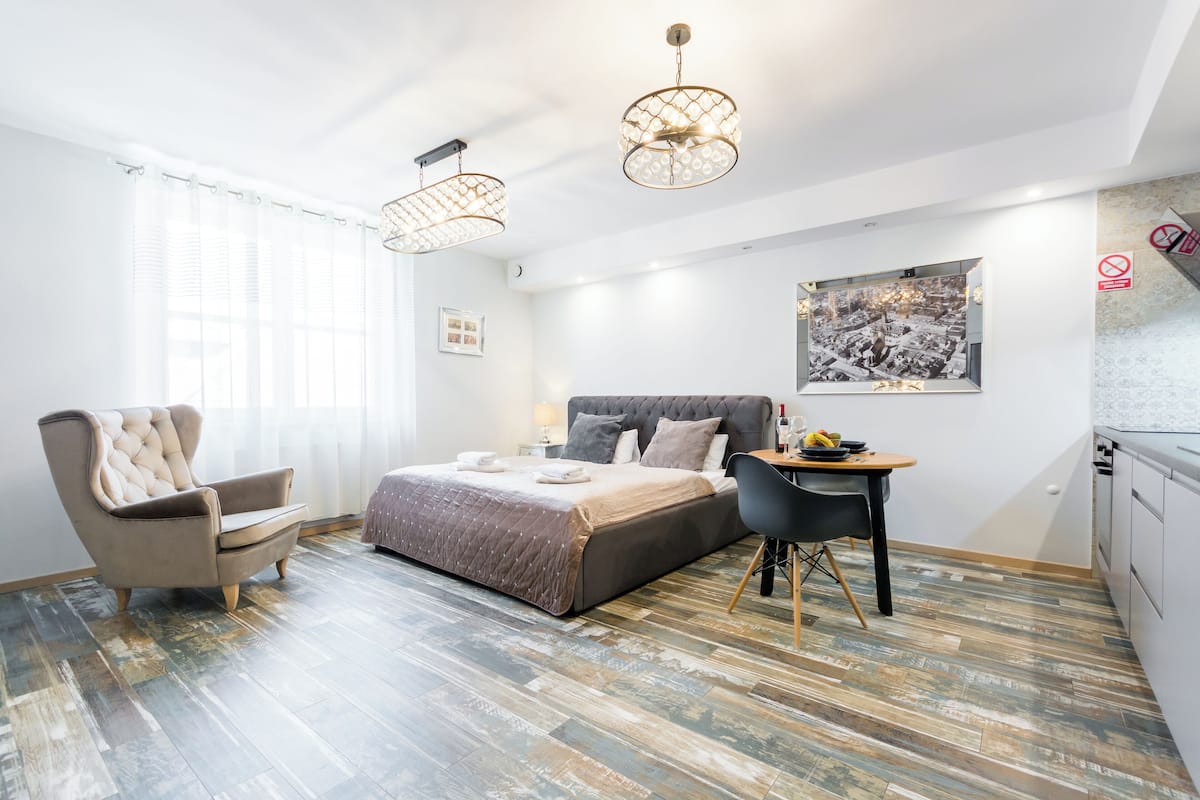 Quarto moderno com cama grande, uma cadeira, uma mesa pequena e um espaço para refeições.