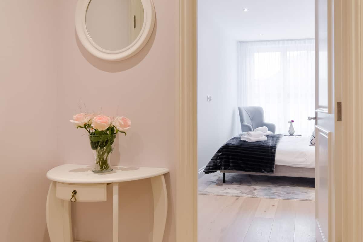 Casa de banho com toucador branco e um vaso de flores cor-de-rosa.
