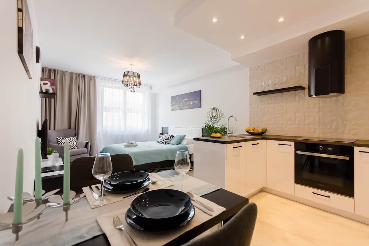 Quarto de hotel moderno com área de refeições, cozinha compacta e uma cama com vista.