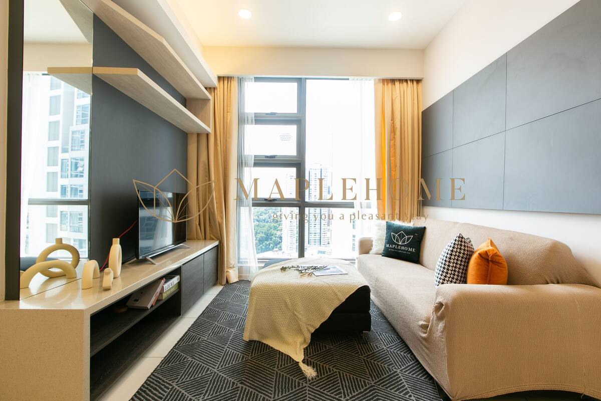 Quarto de hotel moderno com uma janela grande, televisão de tela plana, sofá e mesa de centro.