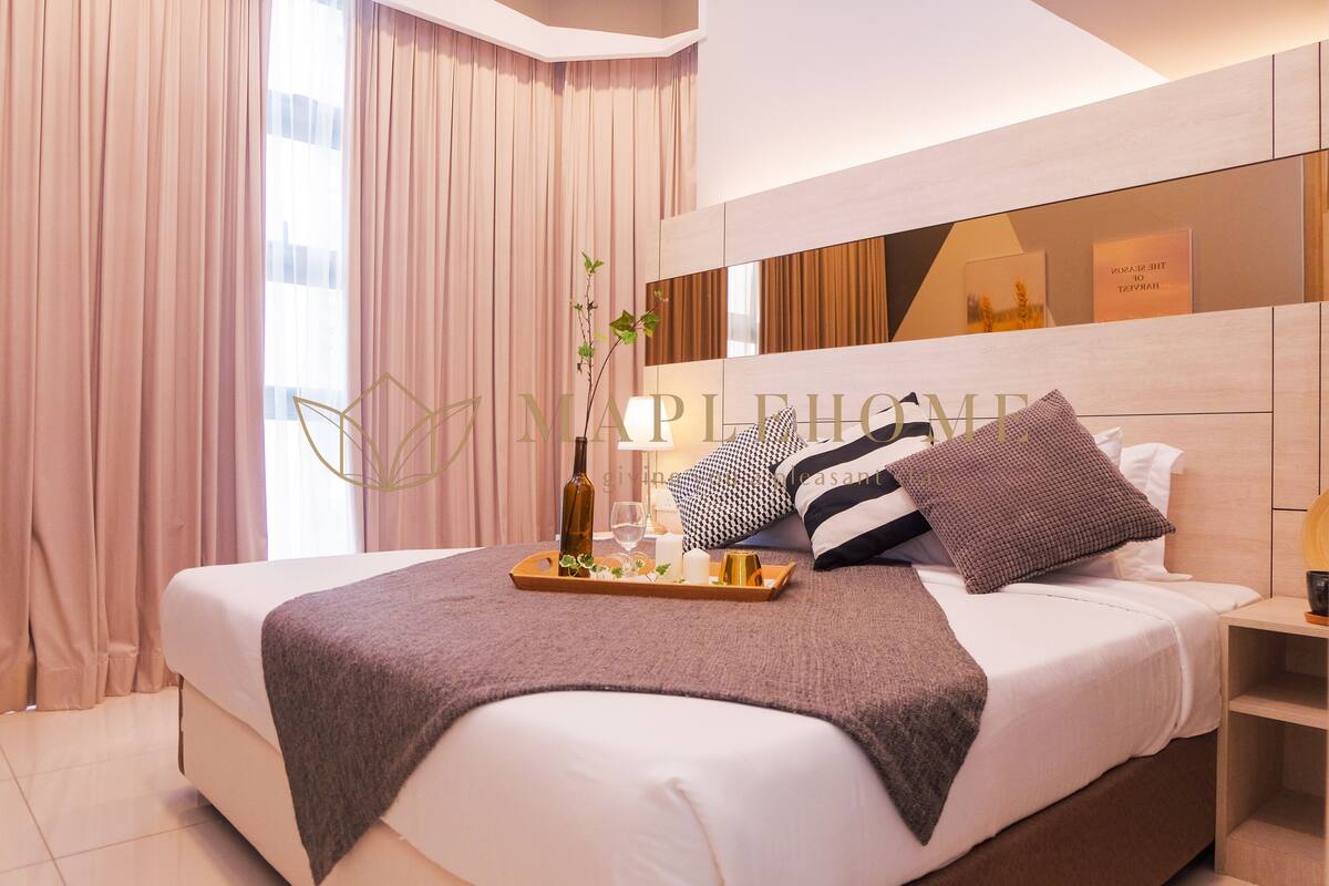 Quarto moderno com cama bem arrumada, mesa de cabeceira e uma janela grande com cortinas.