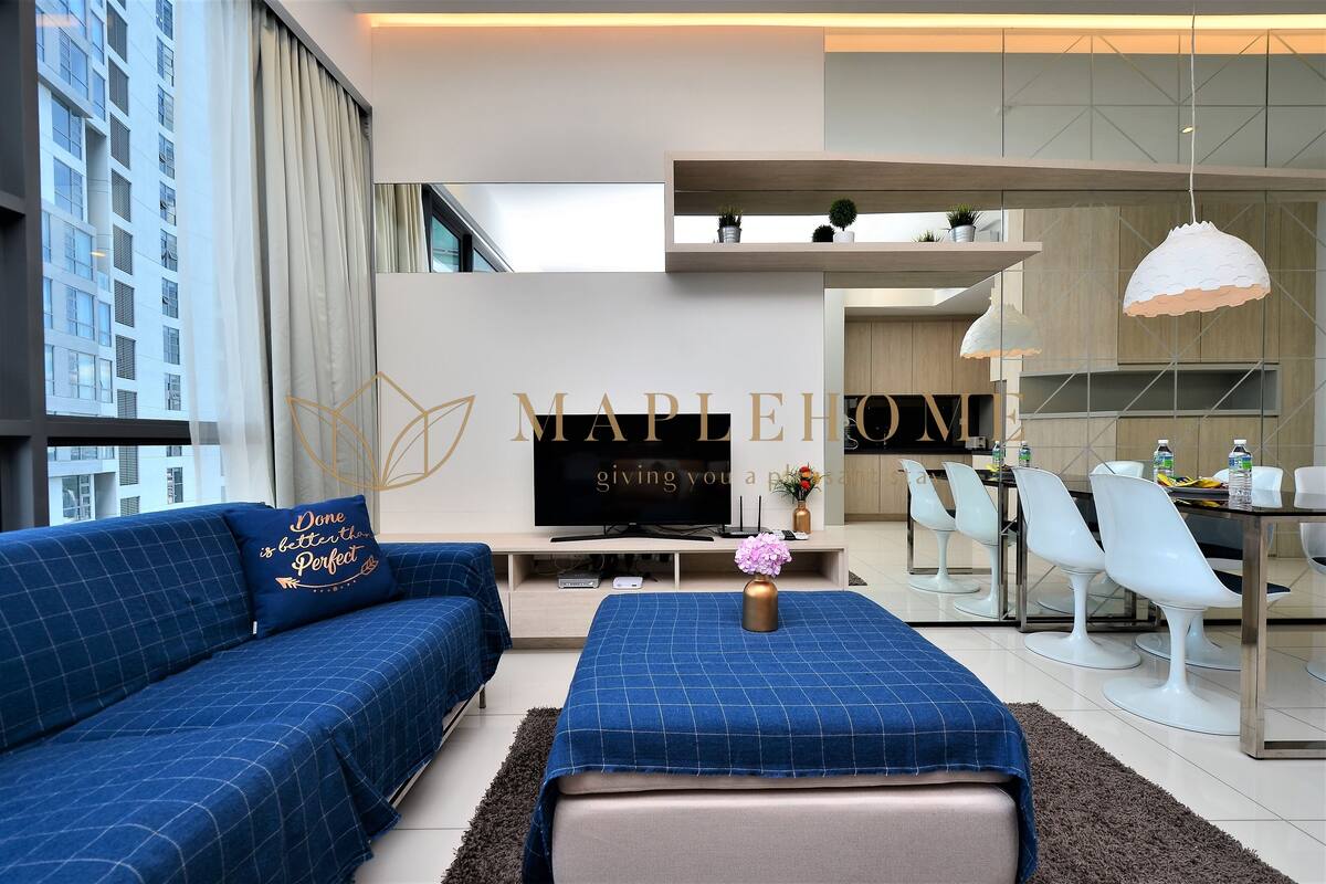 Uma sala de estar moderna com sofá, puf e área de jantar com cadeiras e mesa.
