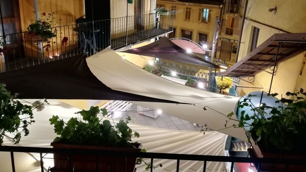 Pátio com uma tenda branca, plantas em vasos e grade de metal.