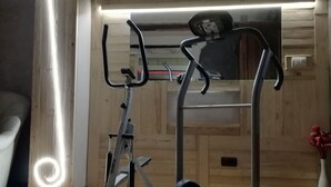 Academia com equipamentos de ginástica, paredes de madeira e um espelho.