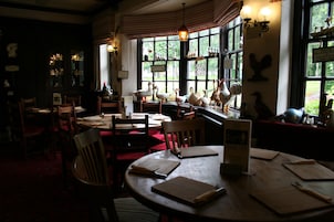 Restaurante com iluminação fraca, mobiliário de madeira e figuras decorativas de cisnes.