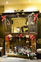 Uma lareira decorada para o Natal, com enfeites vermelhos e dourados, e um espelho acima.