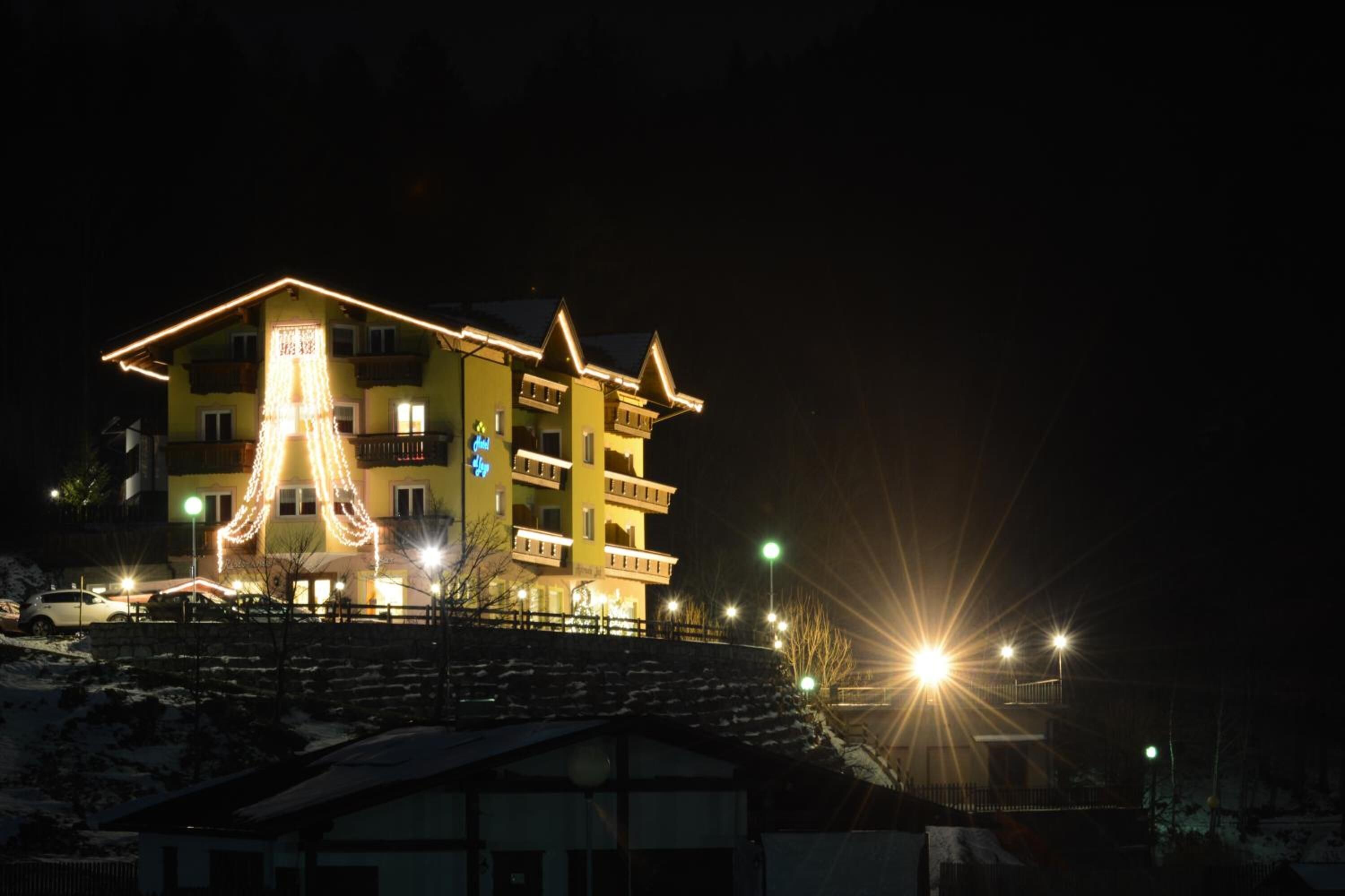 Um edifício de vários andares com varandas e fachada iluminada à noite.