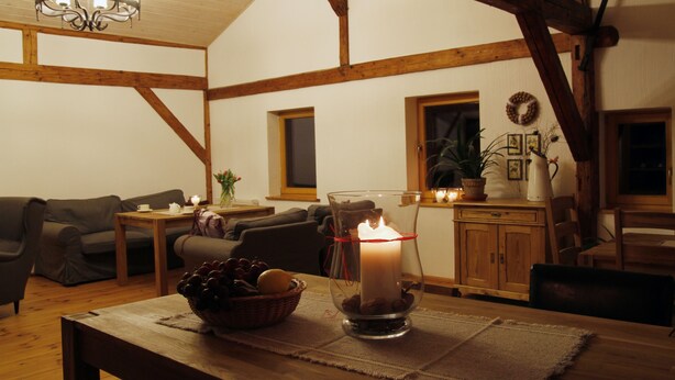 Uma sala de estar acolhedora com uma mesa de madeira, uma vela e uma cesta de frutas.