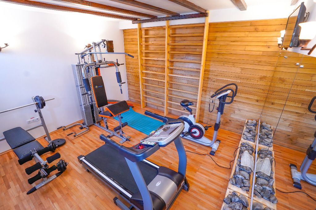 Uma academia com equipamentos de exercícios, incluindo esteira, pesos e remo.