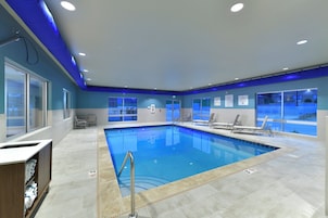 Piscina com água cristalina, rodeada por espreguiçadeiras e piso cerâmico.