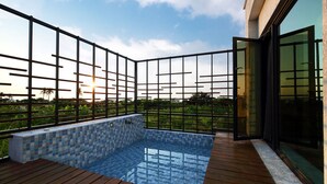 Piscina exterior moderna com deck de madeira, rodeada por uma vedação de metal e uma porta de vidro que dá para um edifício.
