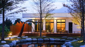 Uma casa moderna com uma grande janela de vidro, um deck de madeira e um lago.