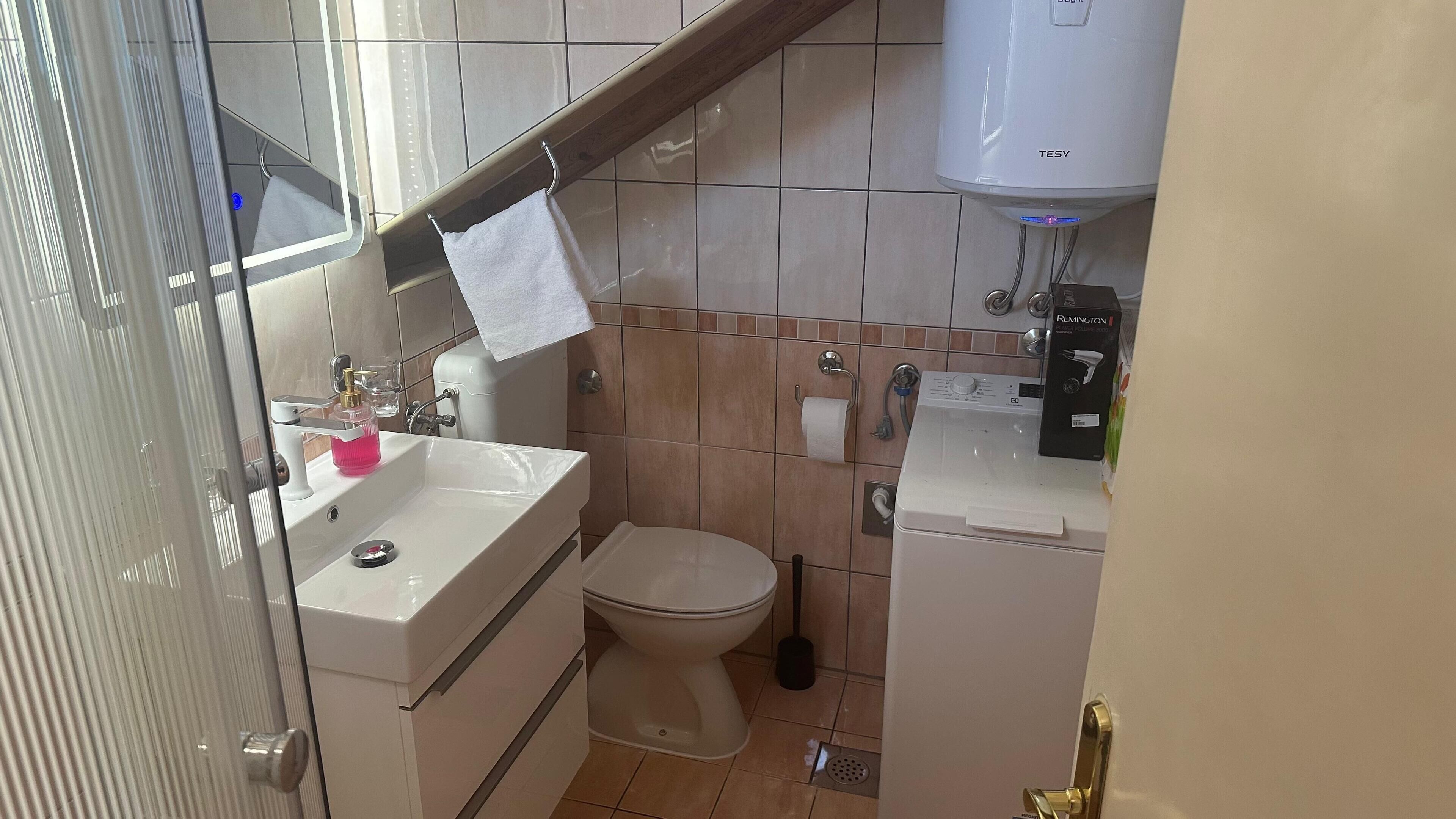 Um banheiro pequeno com pia, vaso sanitário e aquecedor fixado na parede.