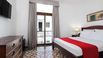 Quarto de hotel com cama, cômoda, televisão, varanda e um quadro na parede.
