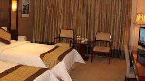 Quarto de hotel com duas camas, uma escrivaninha, uma cadeira e uma televisão.