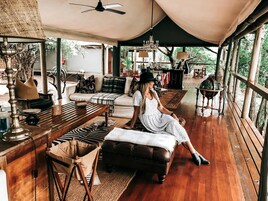 Uma sala de estar espaçosa com sofá, mesa de centro e apoio para os pés, uma mesa de jantar e um ventilador de teto.
