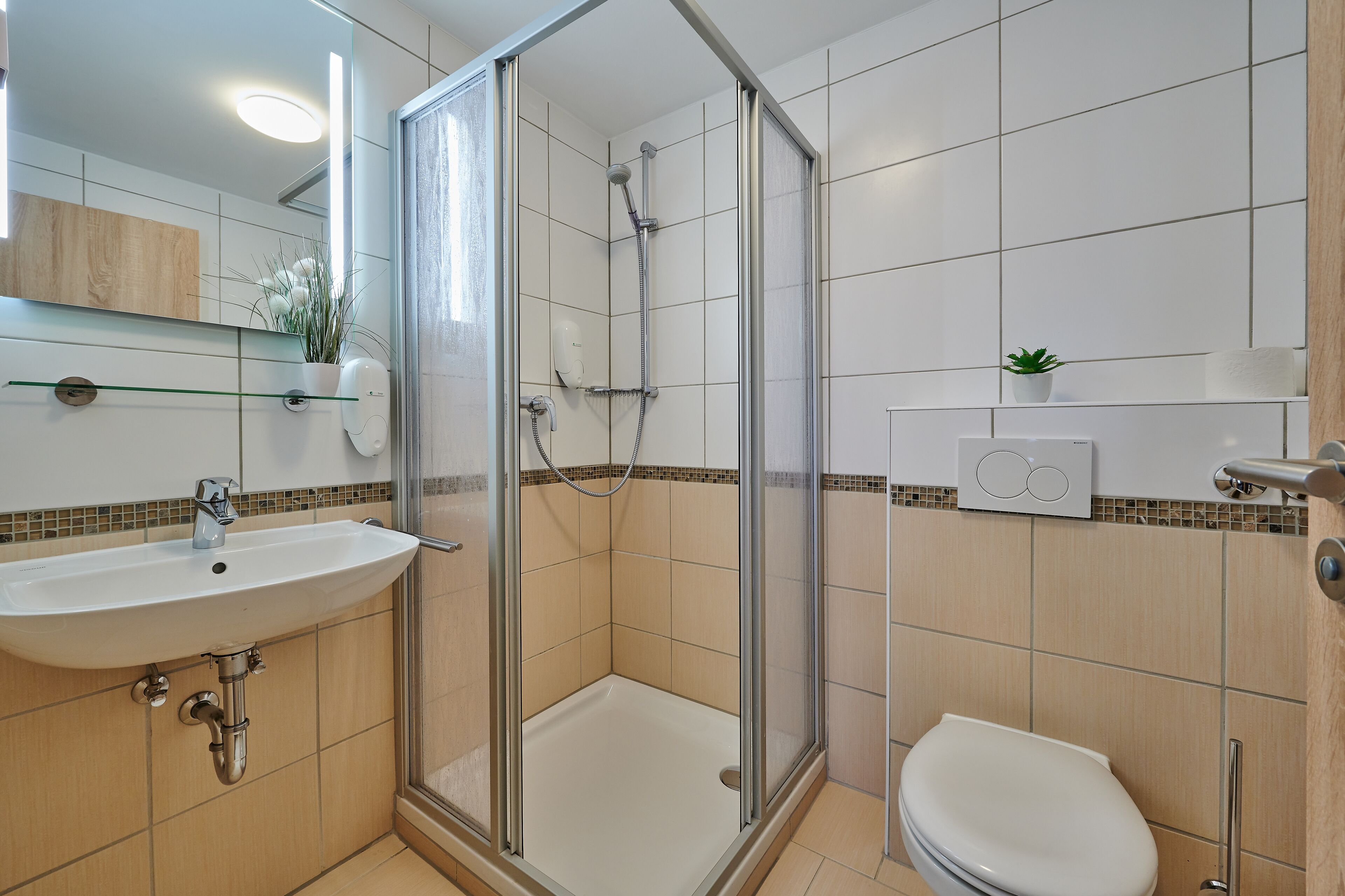 Uma casa de banho moderna com cabine de duche em vidro, lavatório branco e sanita.