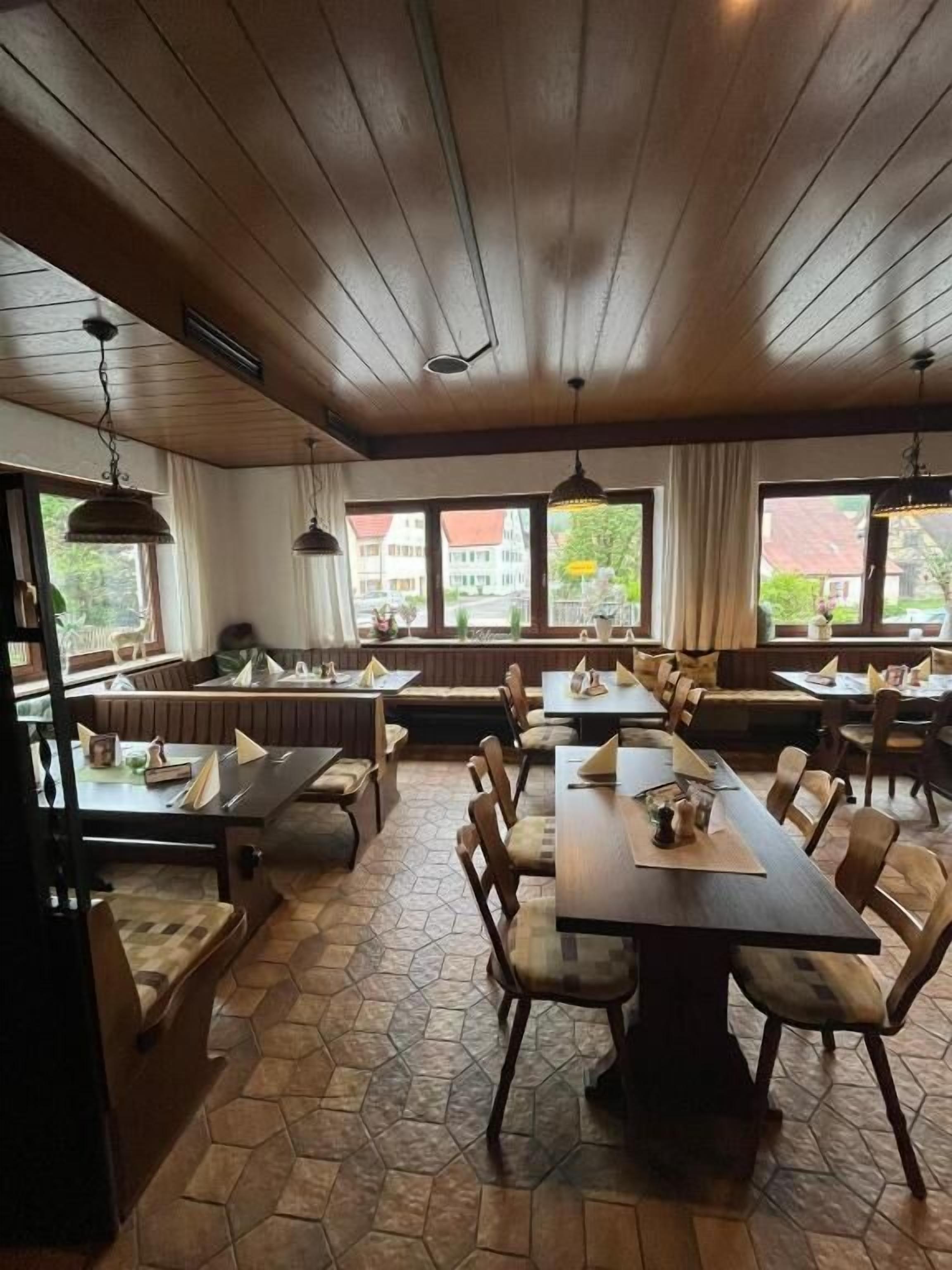 Restaurante com teto de madeira, piso de azulejos hexagonais e mesas com cadeiras.