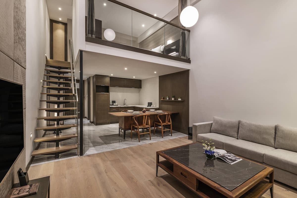 Um interior moderno com escada, área de refeições, sofá e mesa de centro.