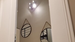 Uma escada com corrimão e luminária acima.