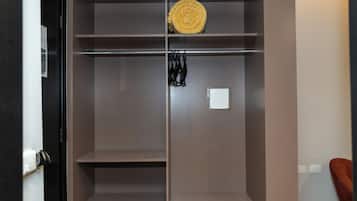 Guarda-roupa fechado com três prateleiras, uma barra para pendurar roupas e um pequeno interruptor branco no lado direito.