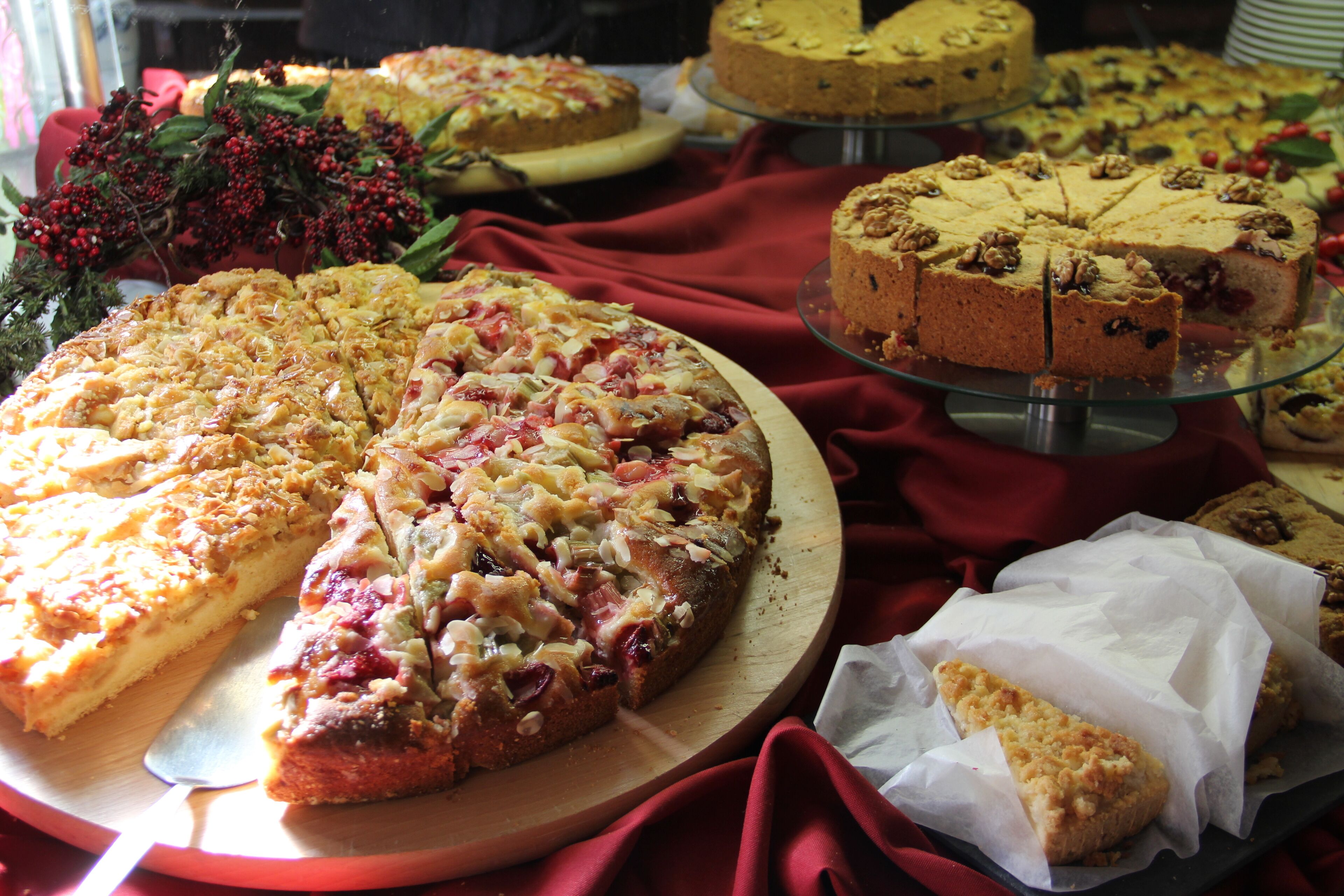Diversas tortas e bolos expostos, incluindo uma torta grande com várias fatias já retiradas.
