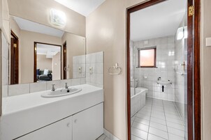 Um banheiro moderno com um espelho grande, duas pias, chuveiro e vaso sanitário.