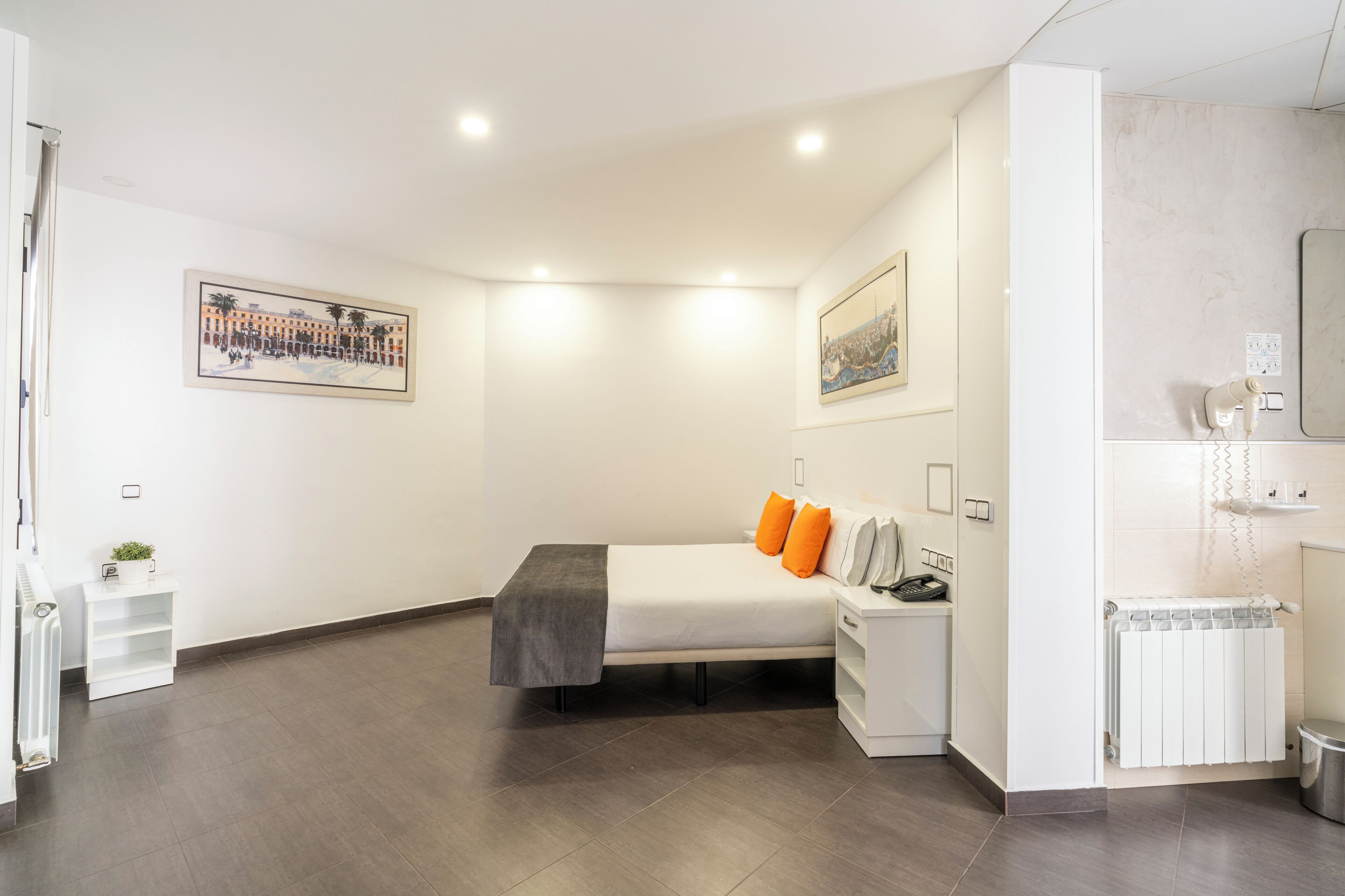 Quarto de hotel moderno com cama, mesa de cabeceira e radiador.
