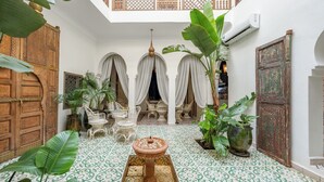 Um pátio com uma fonte, plantas em vasos e uma porta de madeira tradicional.