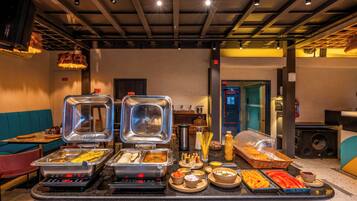 Uma área de buffet com diversas opções de comida e diferentes arranjos de assentos.