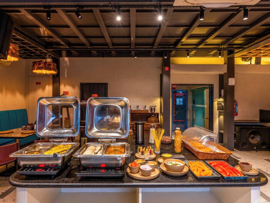 Uma área de buffet com diversas opções de comida e diferentes arranjos de assentos.