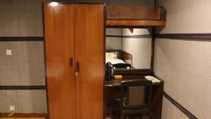 Quarto com armário de madeira, uma escrivaninha e uma cadeira.